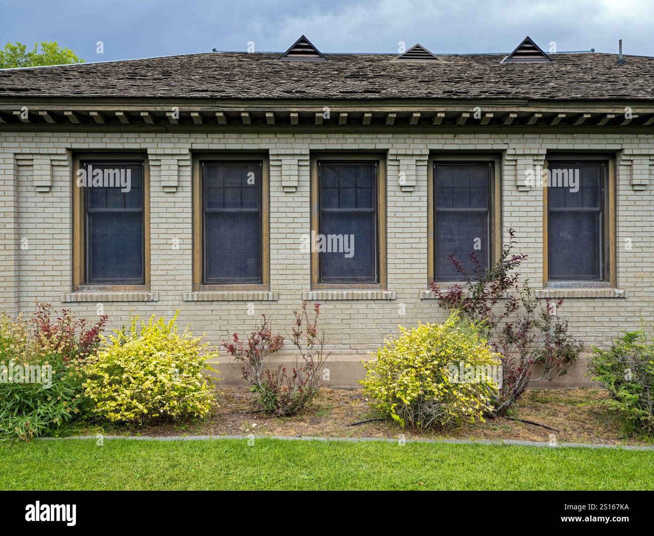 Exterior wall of a tan brick building with triangular roof vents Stock ...