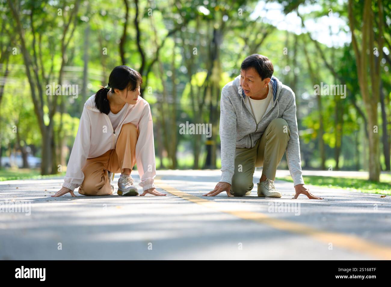 Young woman and middle aged father crouching down in starting position ...