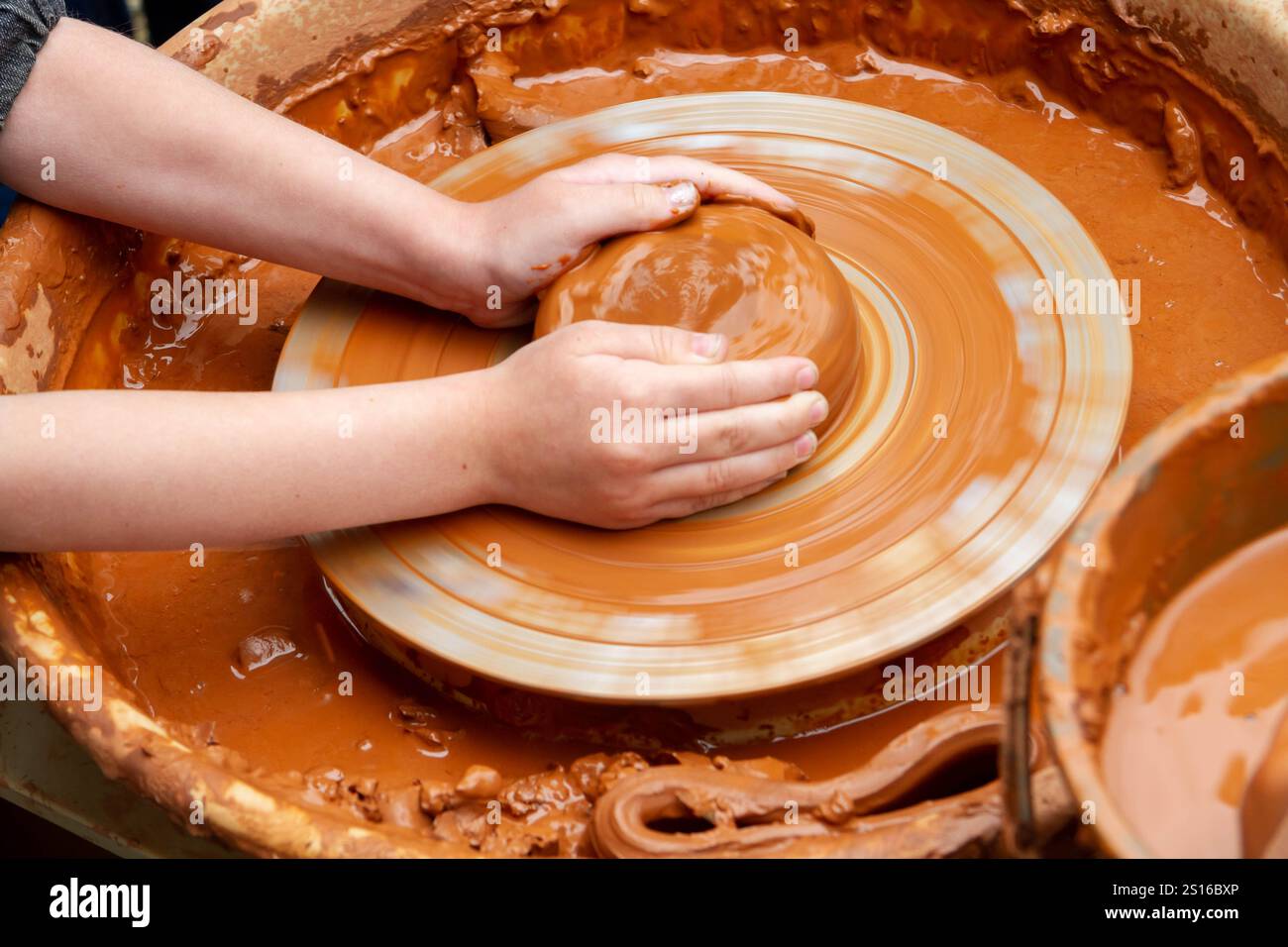 Pottery training. Rotating a clay pot on a machine. Hands knead clay ...