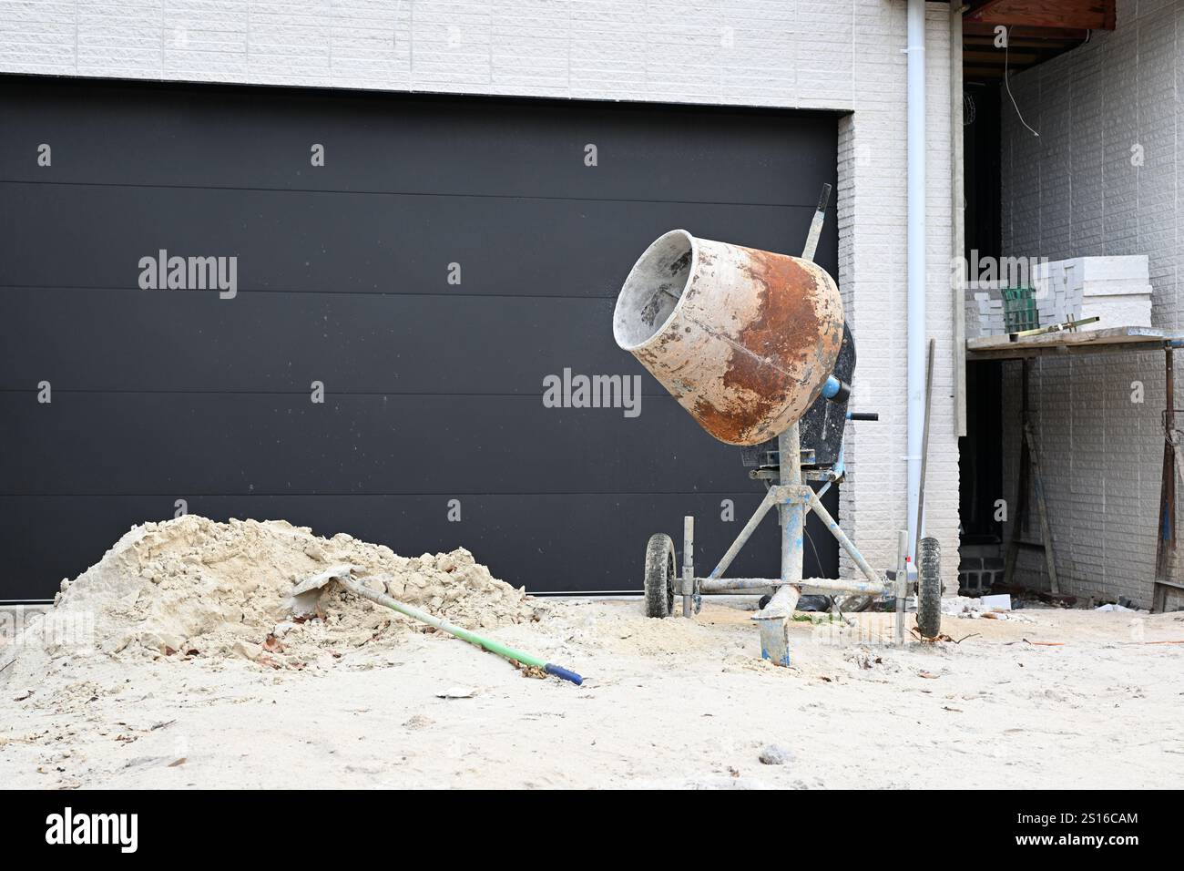 Cement mixer machine in a building site, outside the garage door of a ...