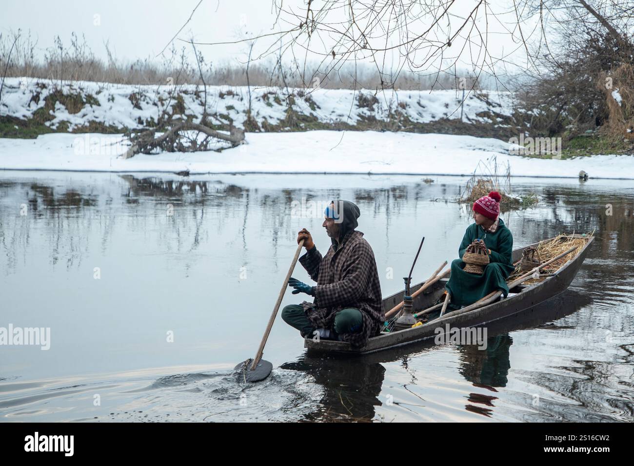 Ganderbal, India. 01st Jan, 2025. A Kashmiri man with his son rows his ...