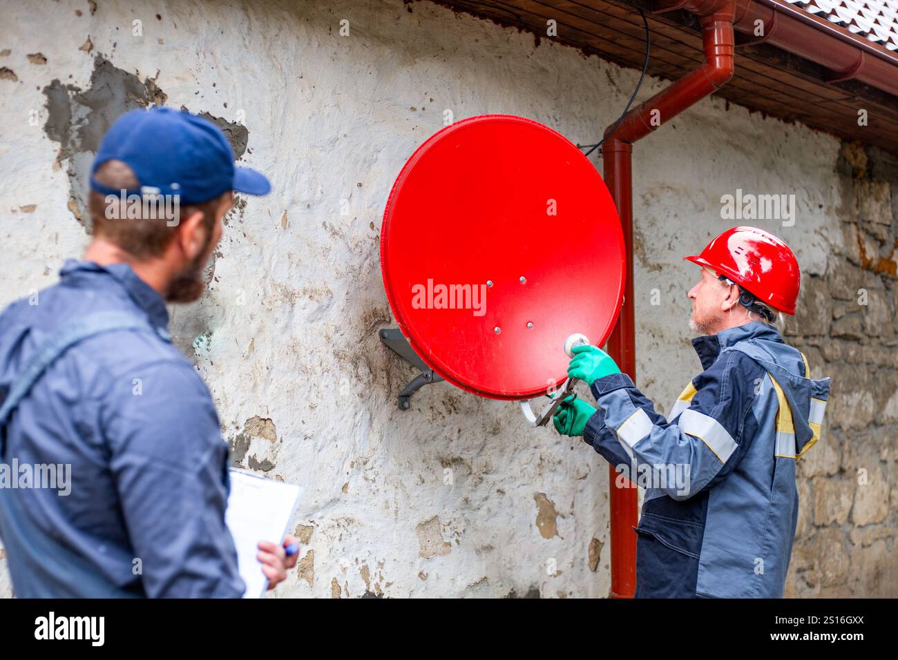 Workers install a MTS satellite TV antenna to receive a signal ...