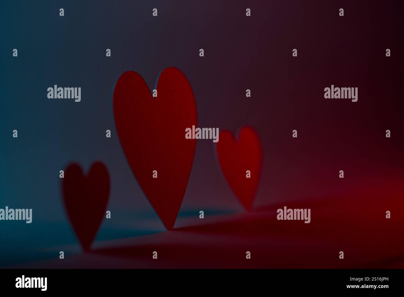 Oblique angle of three hearts in a dark red and pink against a bluish ...