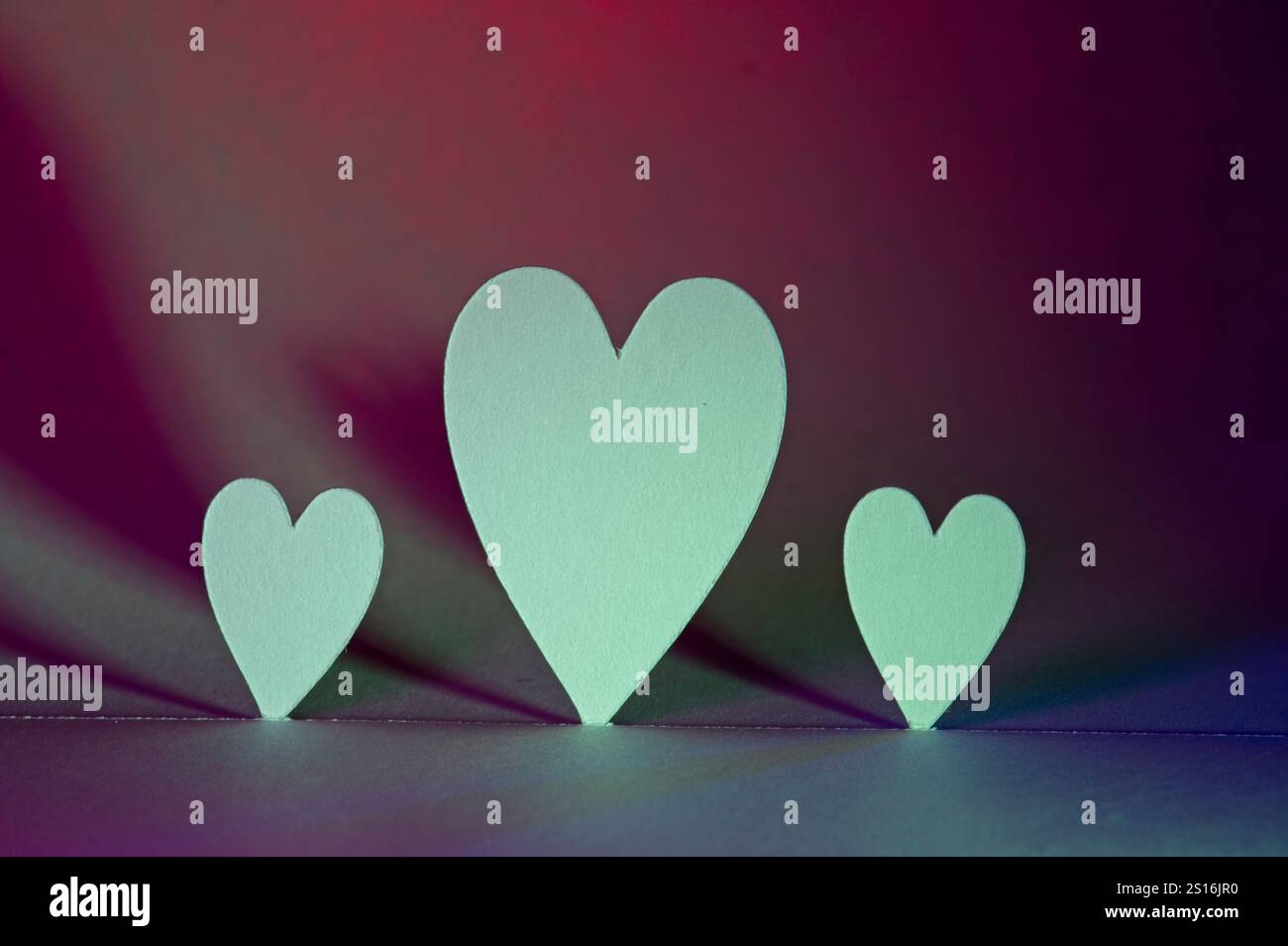 3 White Hearts standing in front of a pinkish lit background Stock ...