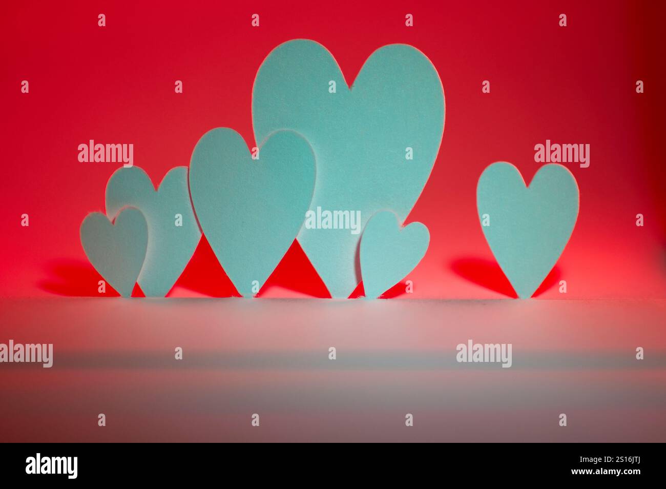Paper heart cutouts against a red to pink background Stock Photo - Alamy
