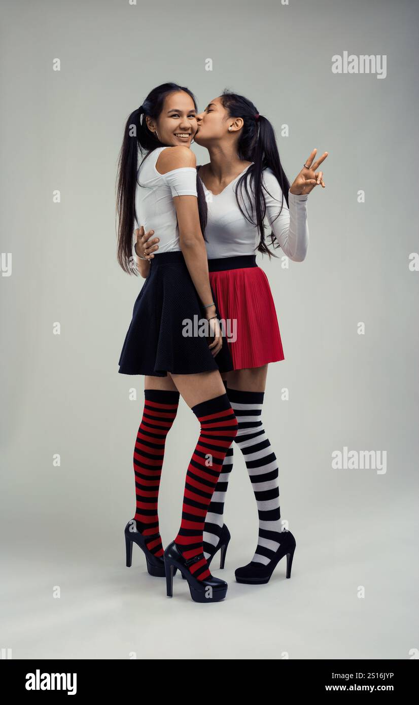 Two cheerful young women posing together in a studio, wearing colorful ...