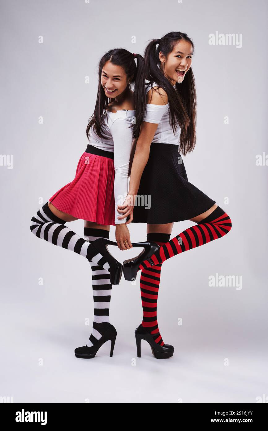 Two happy teenage girls wearing colorful miniskirts, striped socks and ...