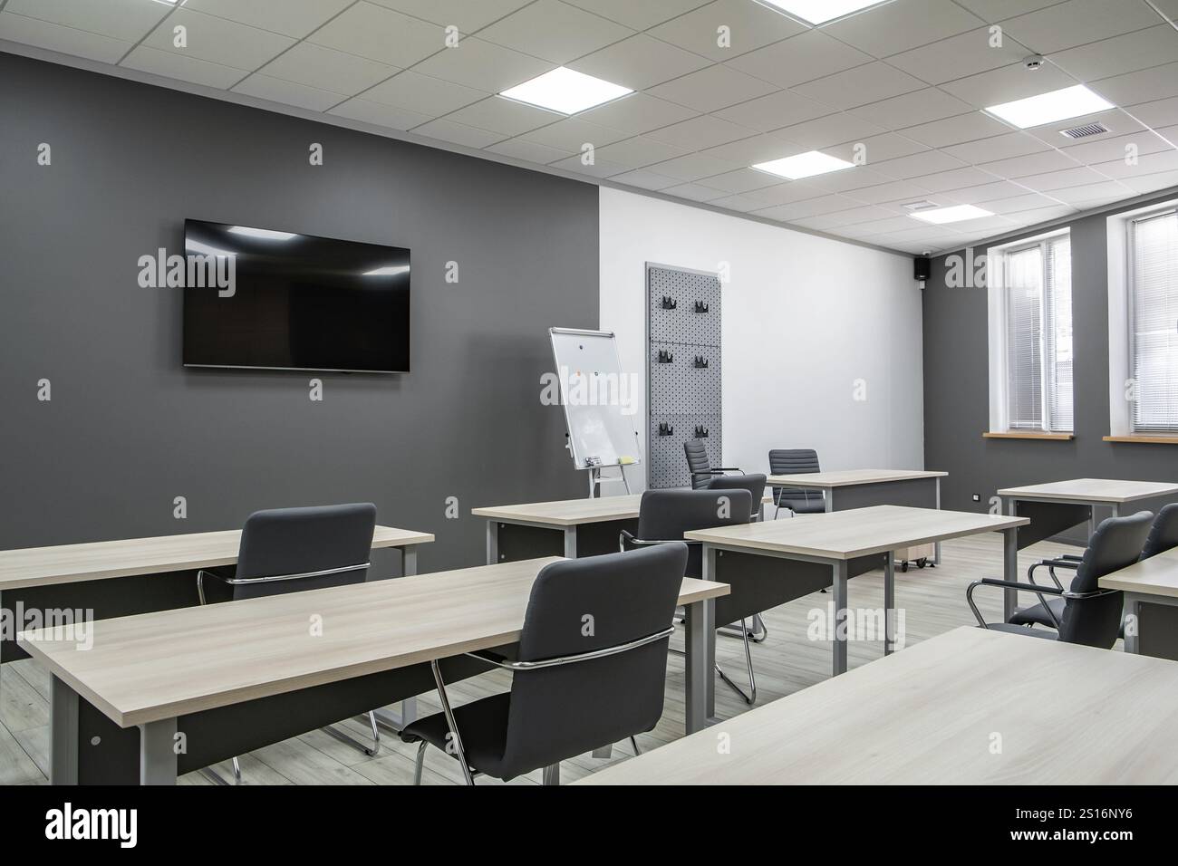Modern classroom or office space with desks and chairs, a large wall ...