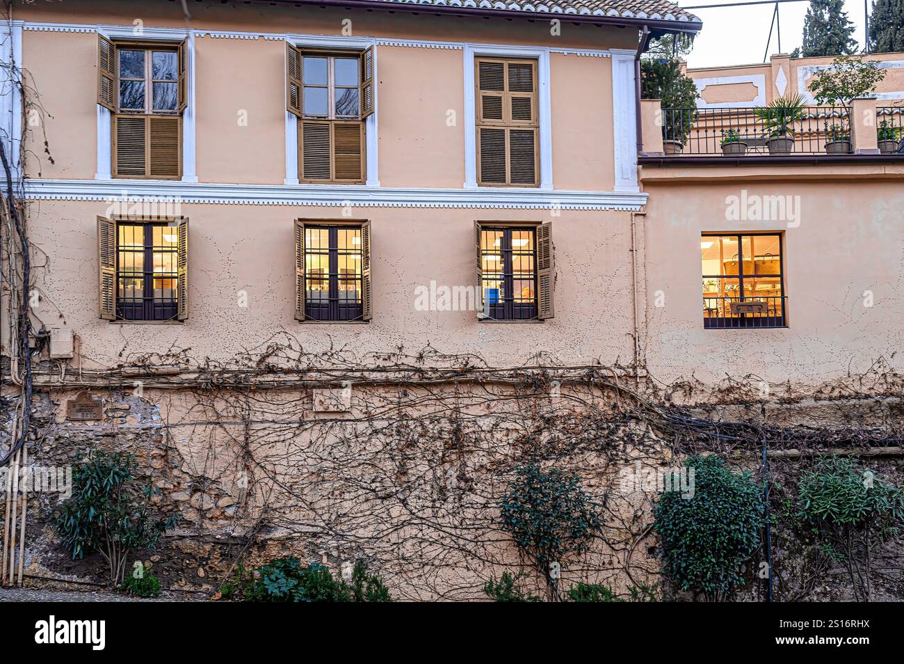 Illuminated windows on the lateral wall of an old building exterior ...