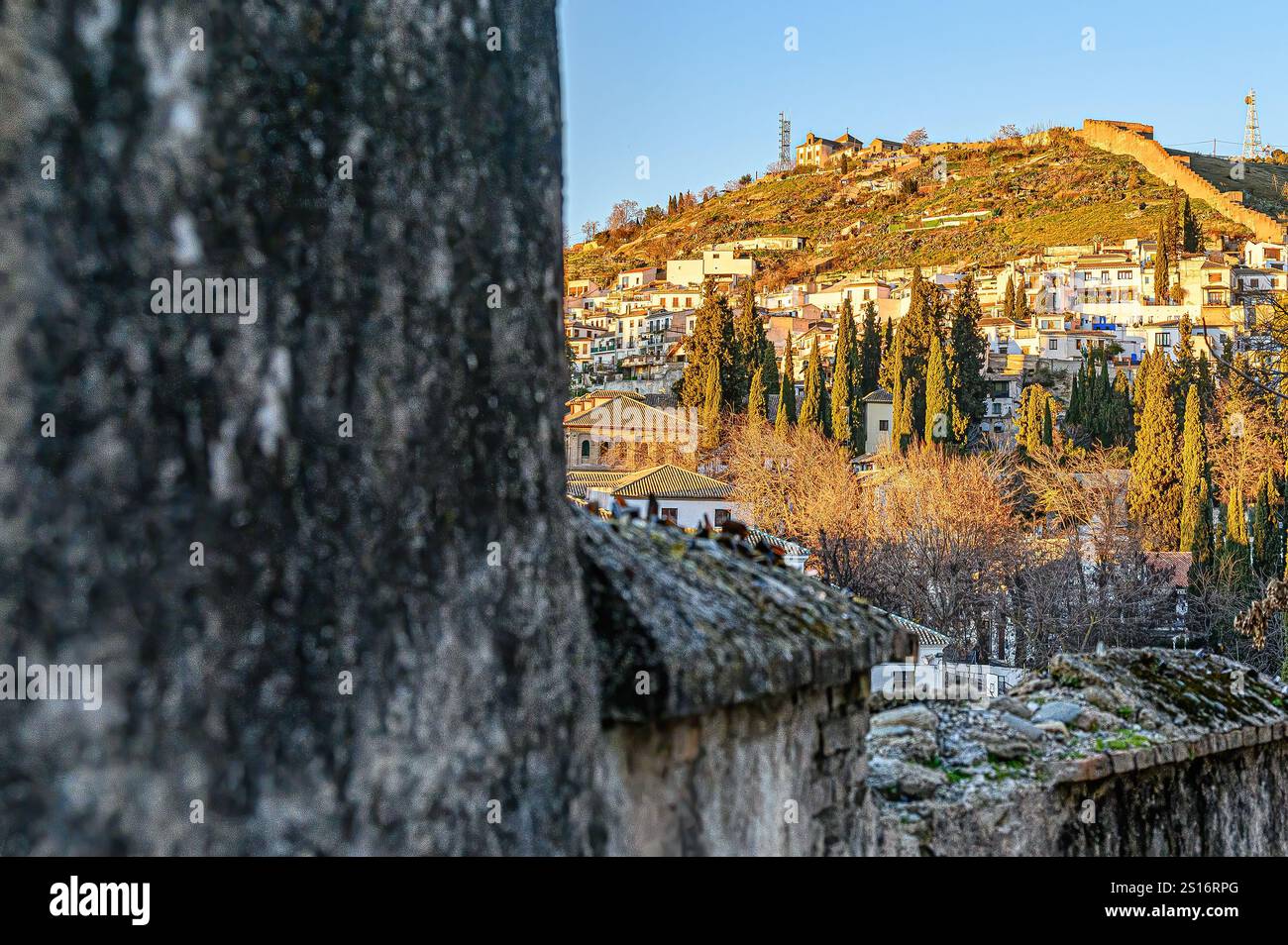 Townscape buildings framed by the medieval stone wall of the Alhambra ...