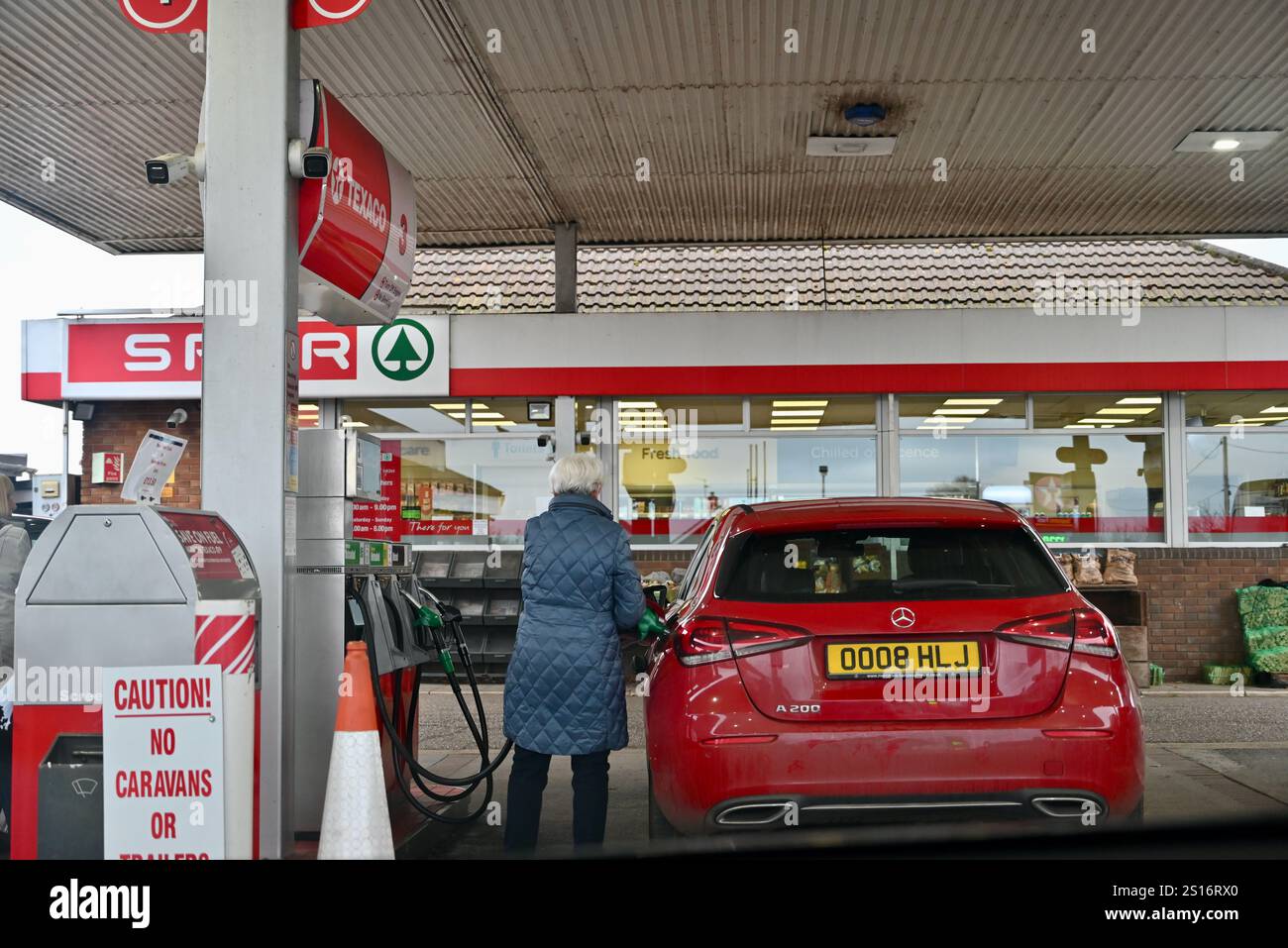 an older woman at the petrol pump in a texaco filling station at ...
