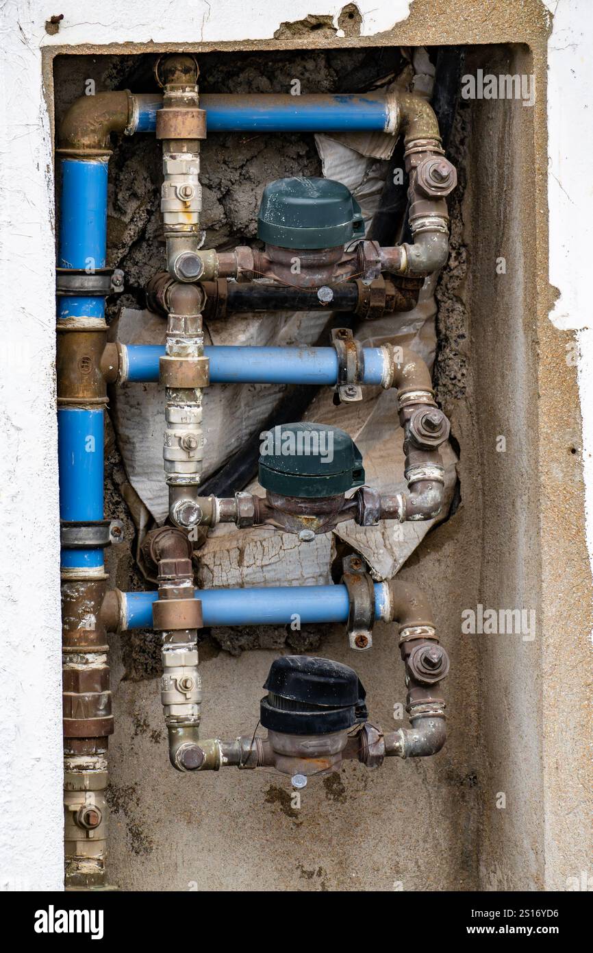 Three pipes are connected to a wall, with a green cap on the middle ...