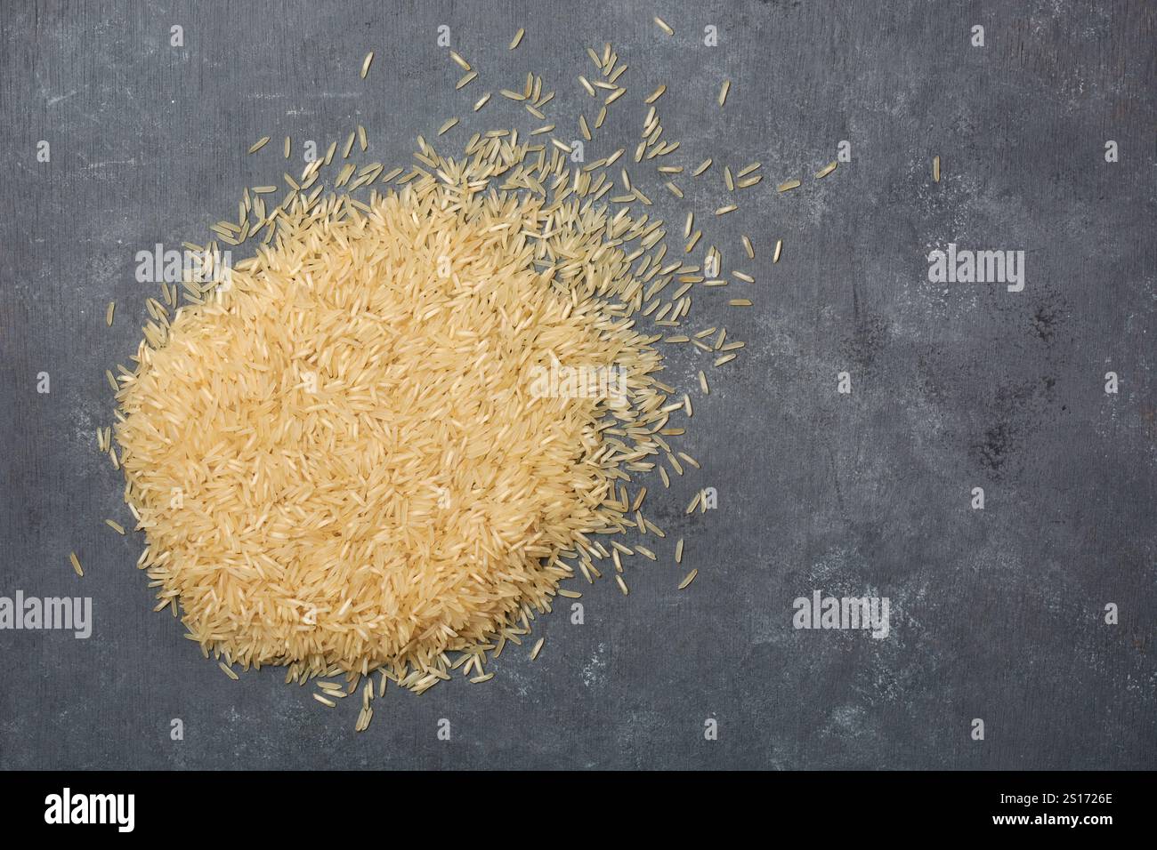 pile of raw basmati rice grains scattered on black textured rustic ...