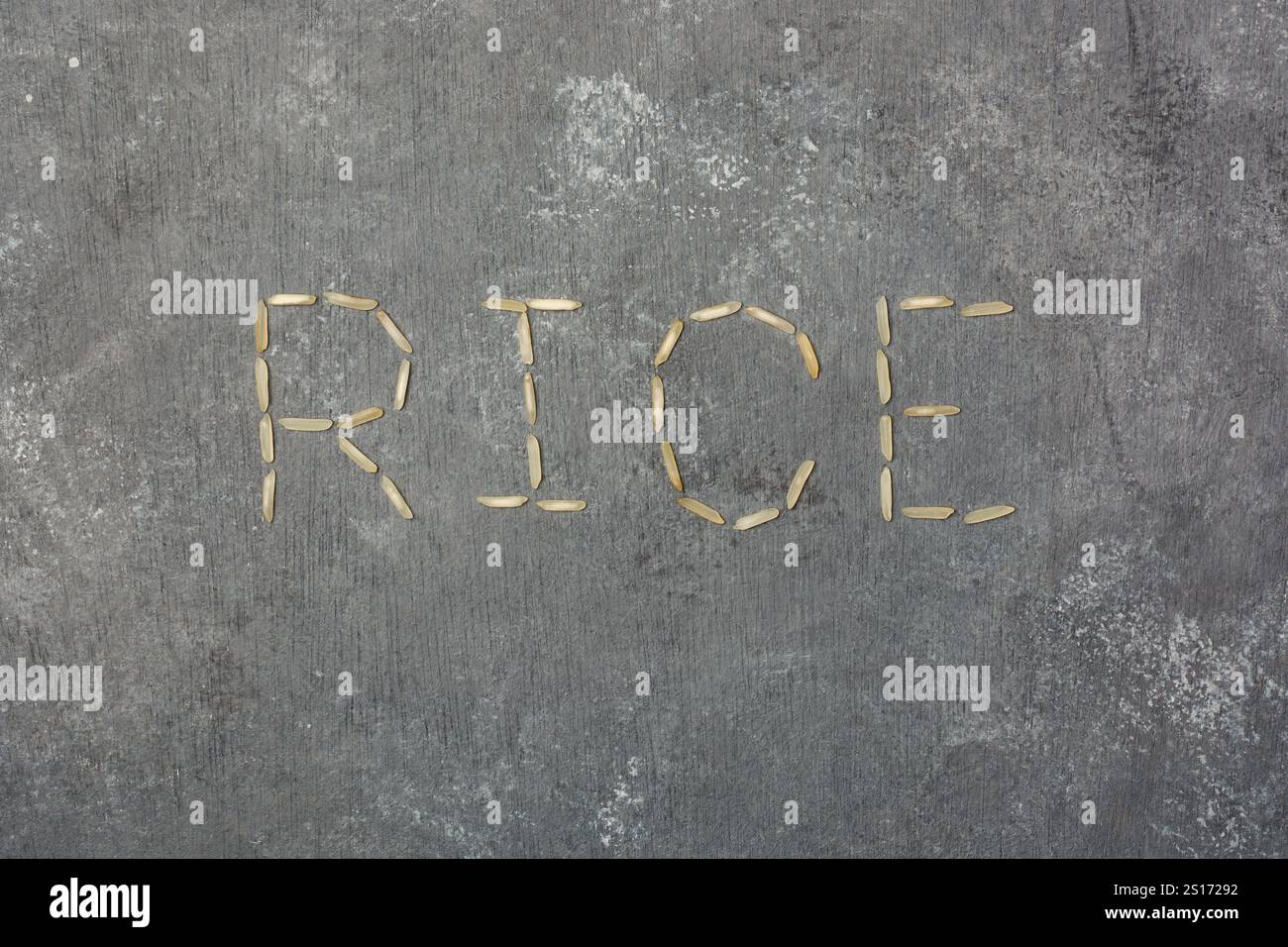word rice with raw rice grains on textured black surface background ...