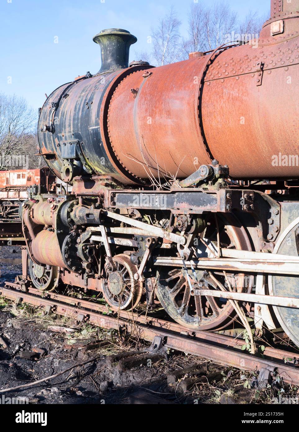 A narrow gauge steam locomotive is rusting away in the yard of the ...