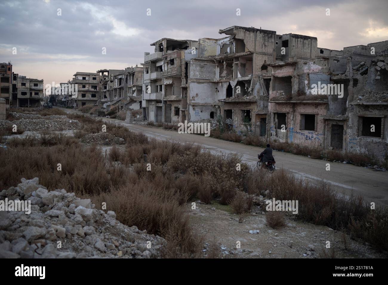 A man rides his motorcycle past buildings that were destroyed during ...