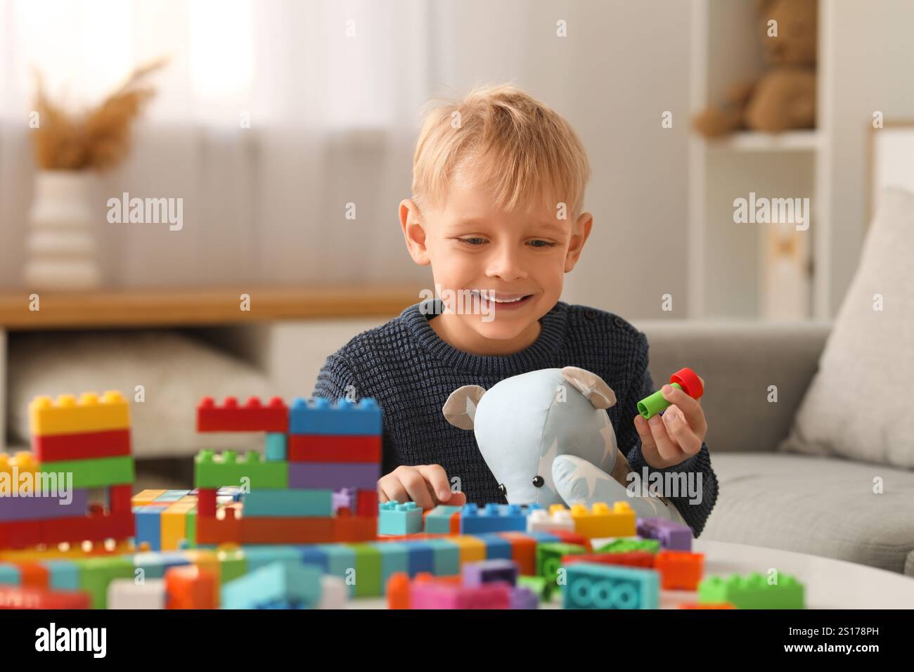Happy cute little boy playing with colorful toy bricks and teddy bear ...