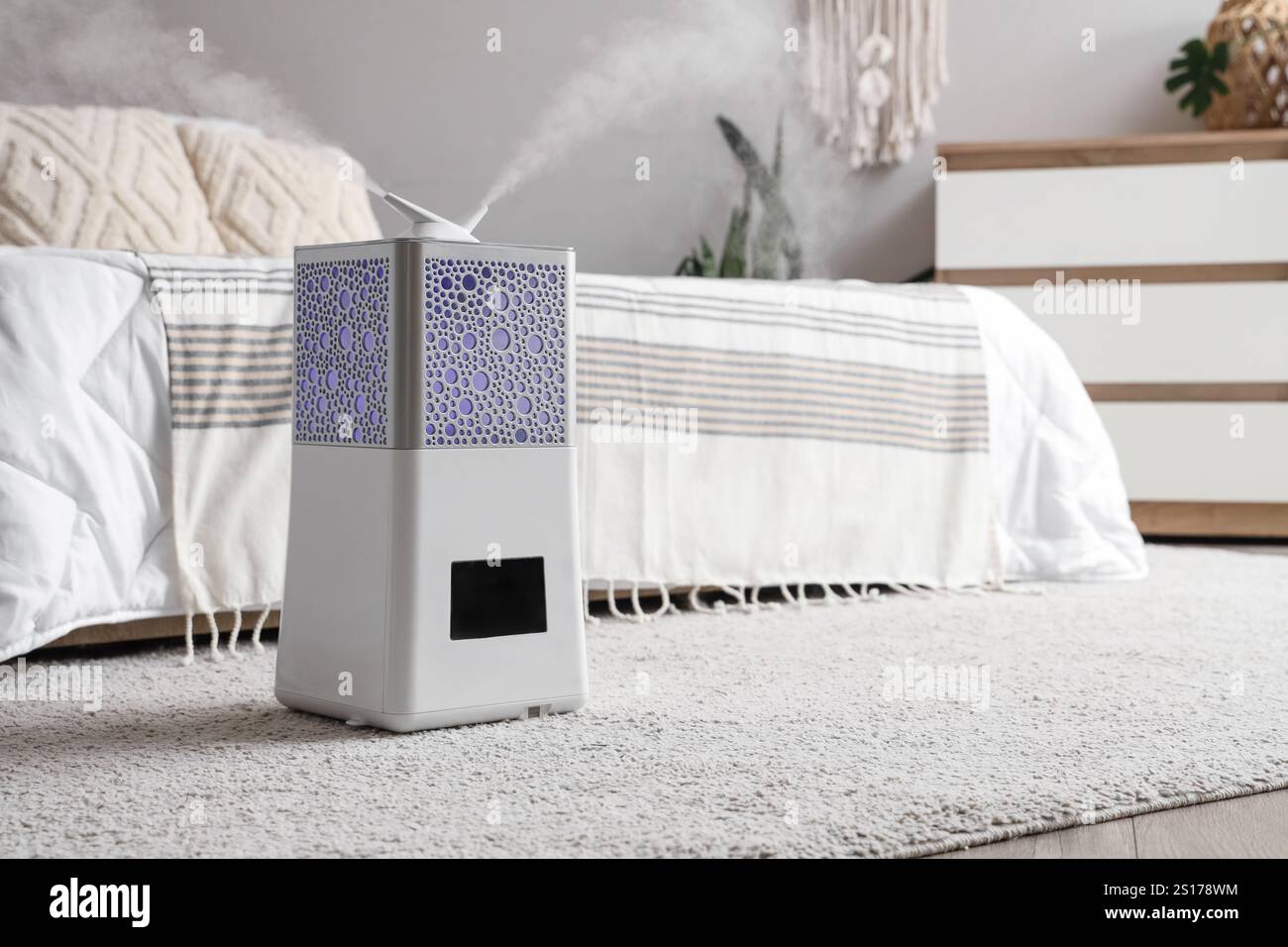 Modern humidifier on floor near bed in bedroom Stock Photo - Alamy