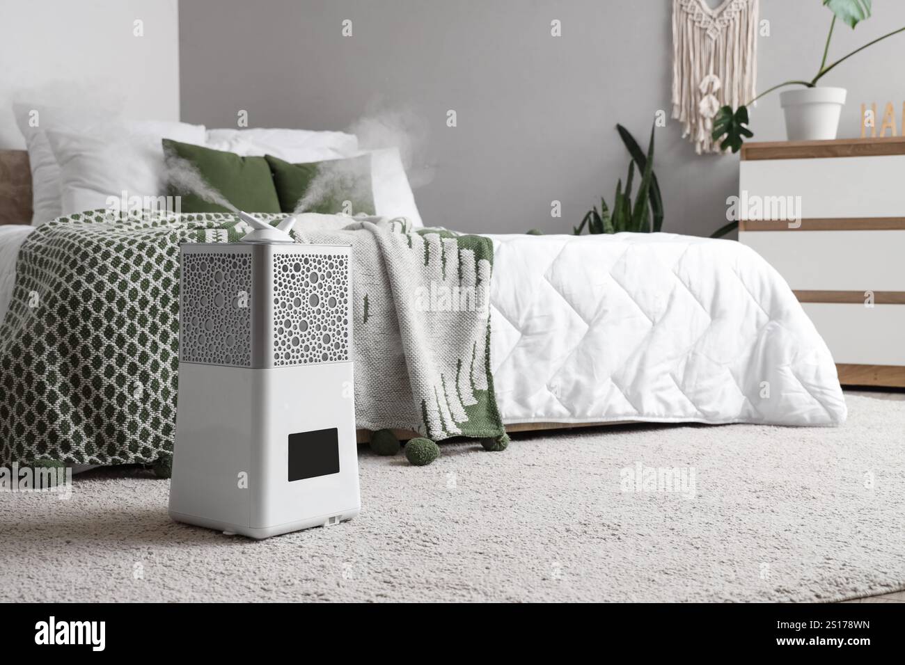 Modern humidifier on floor near bed in bedroom Stock Photo - Alamy