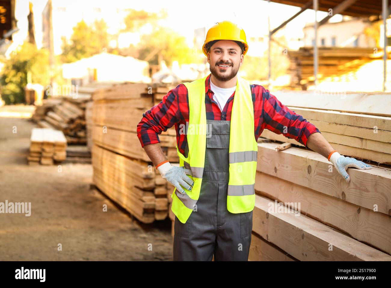 Young carpenter in reflective vest near wooden planks at sawmill Stock ...