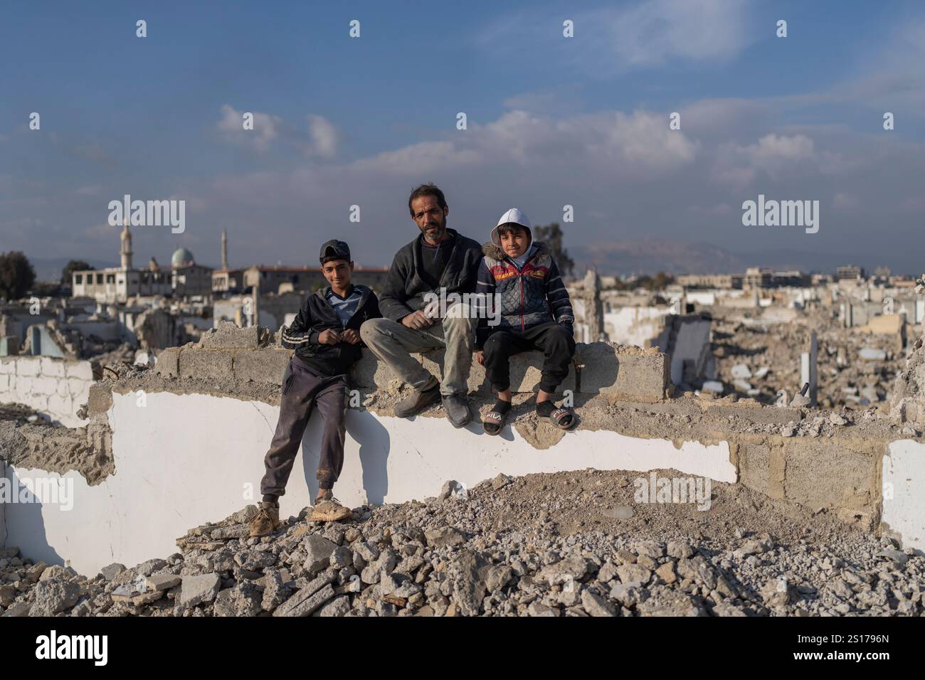Mustafa Al Hanash and his son and nephew sit on the rubble of what used ...