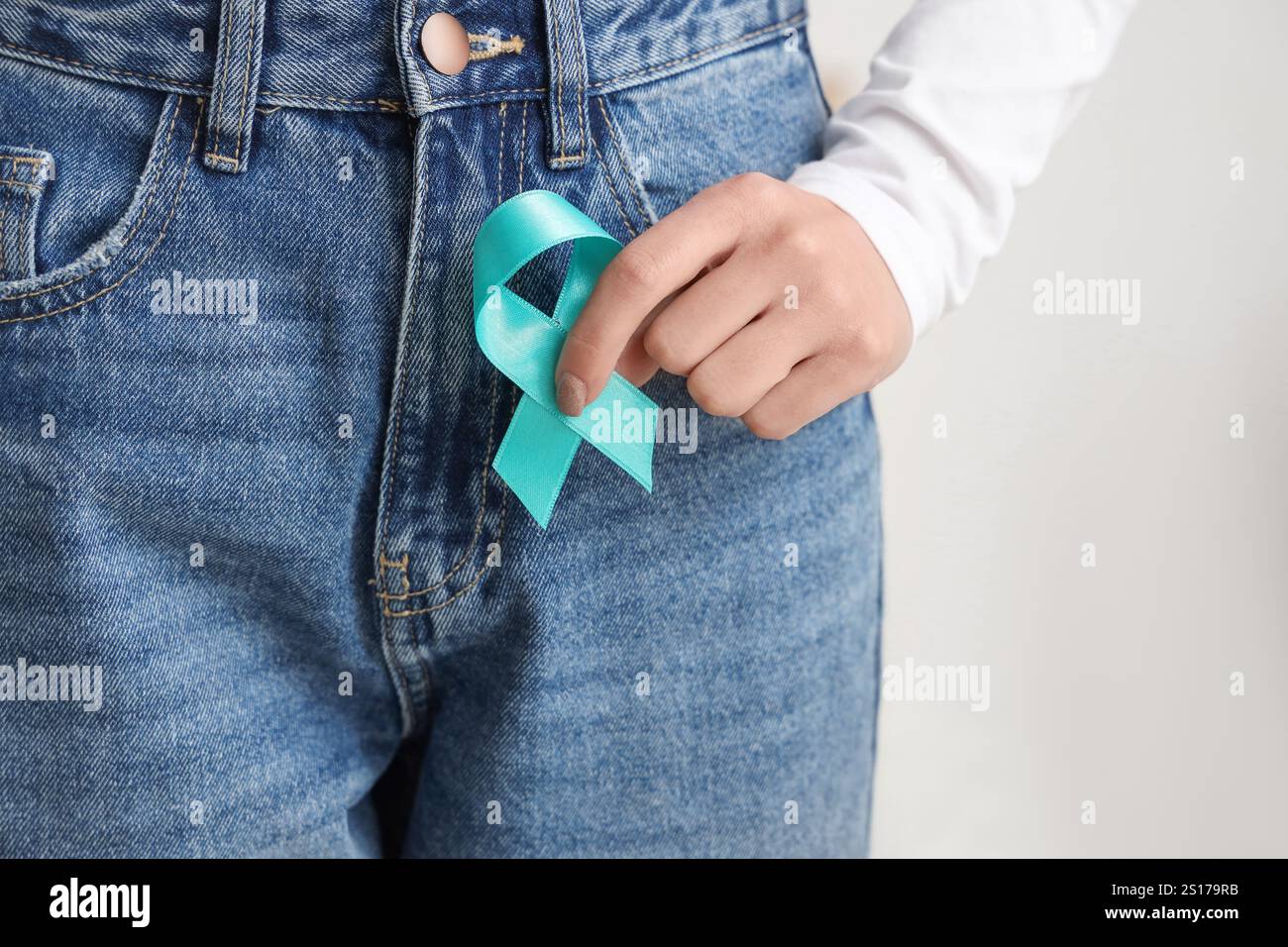 Young woman holding turquoise ribbon in bedroom. Cervical Health ...