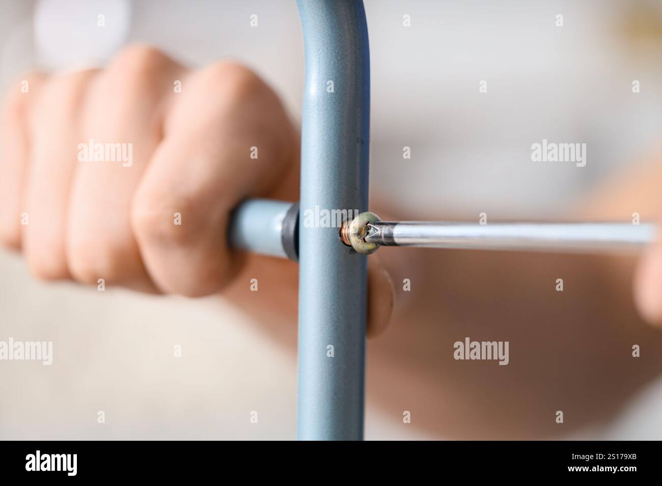 Male worker tightening screw in metal frame with screwdriver, closeup ...