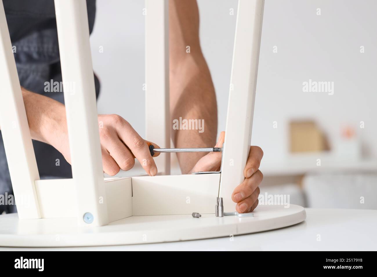 Male carpenter tightening screw in table with screwdriver, closeup ...