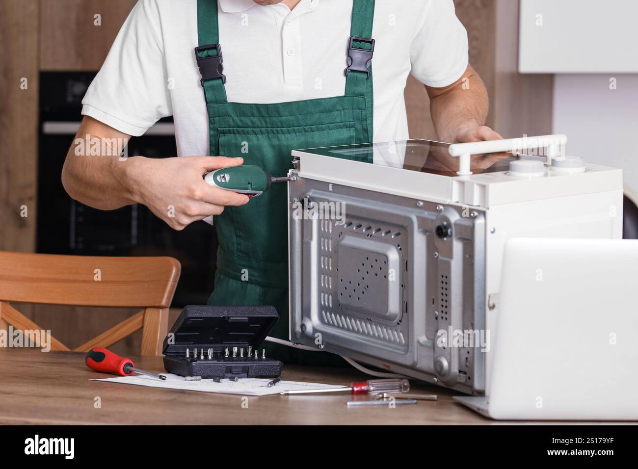 Male technician tightening screw in modern microwave oven with electric screwdriver Stock Photo ...