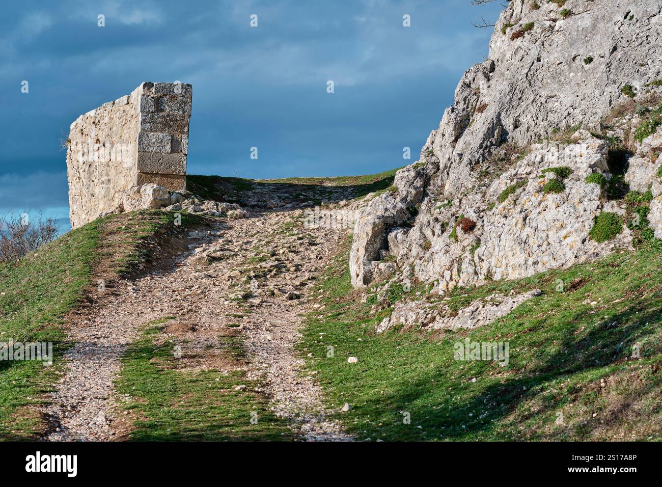 An image of a dirt path leading uphill towards an old stone structure ...