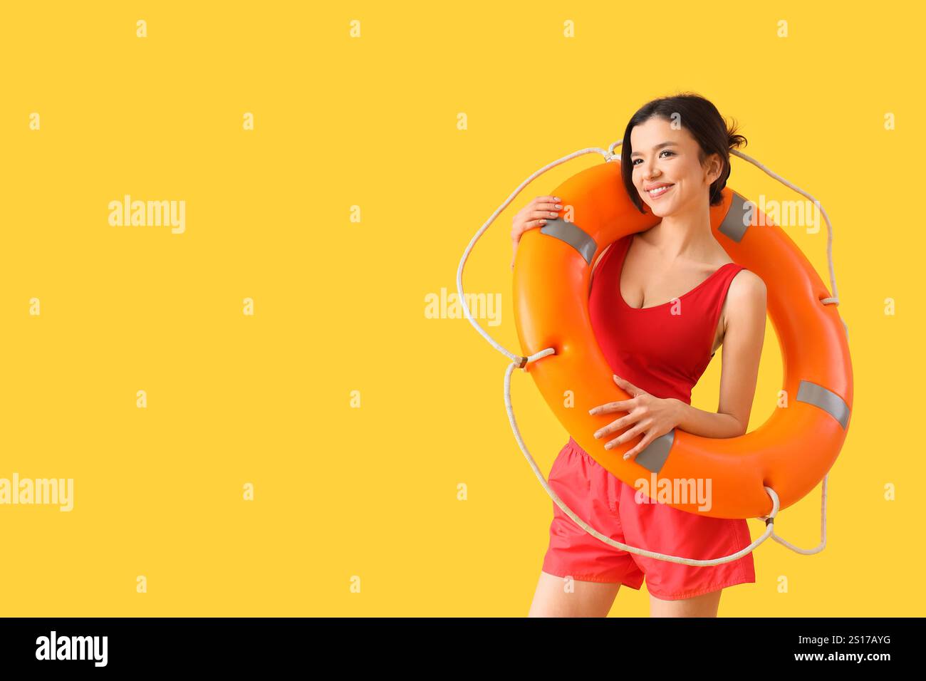 Female lifeguard with rescue ring on yellow background Stock Photo - Alamy