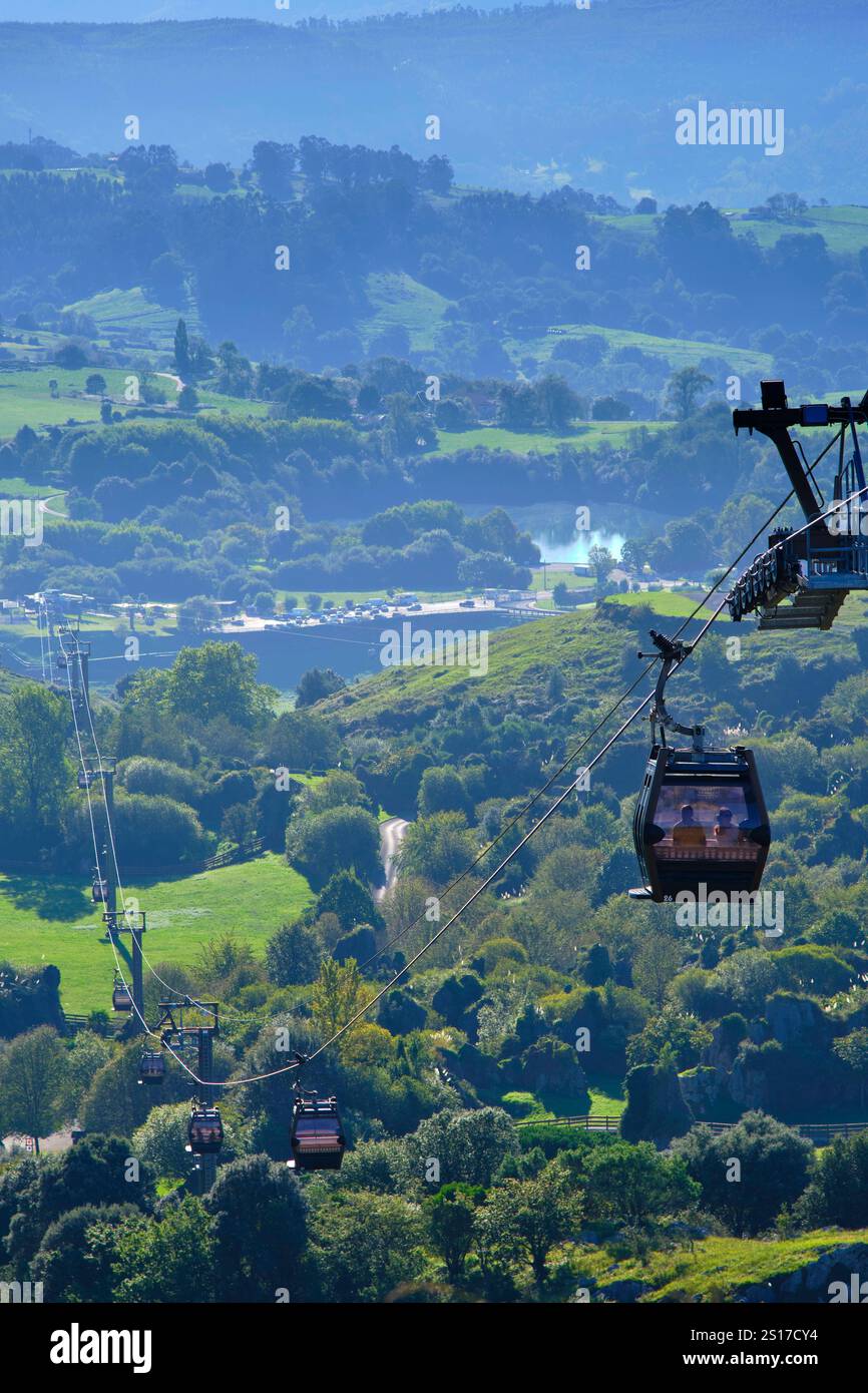 A cable car is suspended above a lush green valley. The cable car is ...