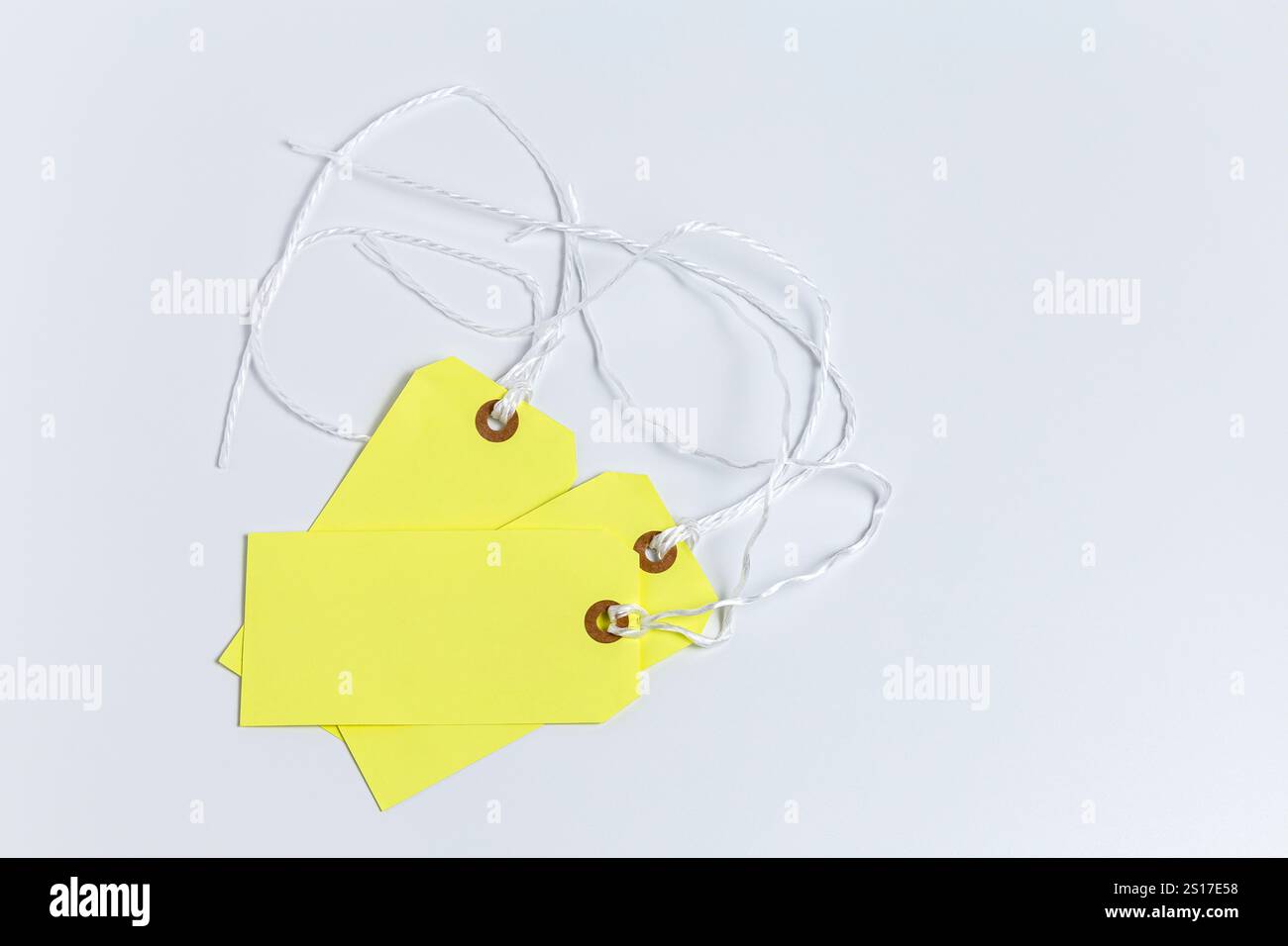 Blank yellow labels on strings on a white surface Stock Photo - Alamy