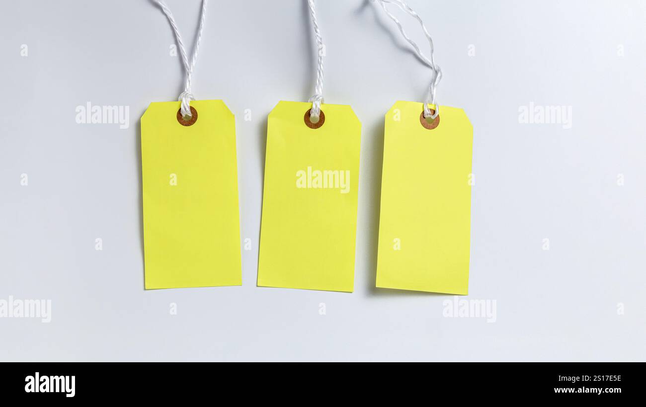 Blank yellow tags hanging on strings on white background Stock Photo ...