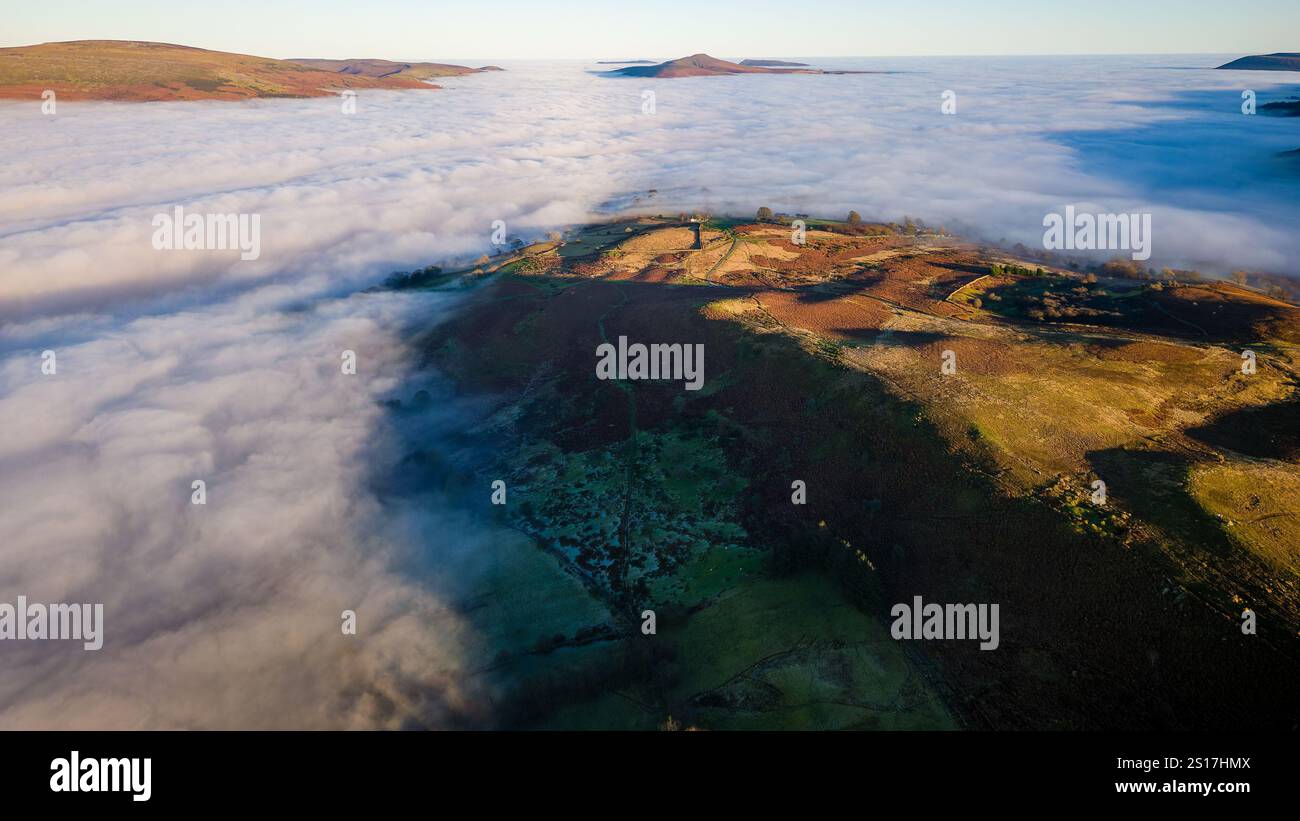 Aerial shot of a fog filled rural valley with rolling hills behind ...