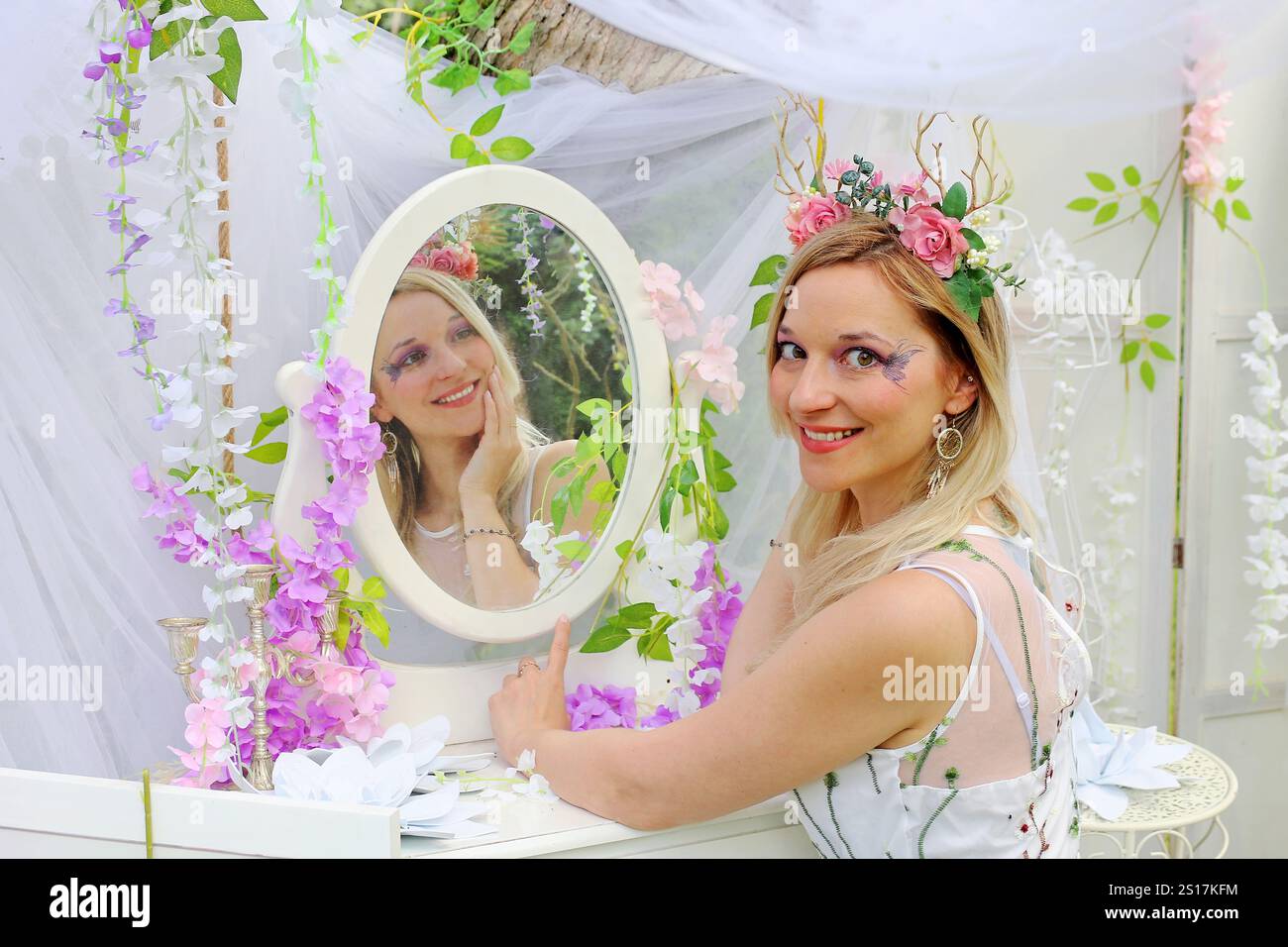 A pretty elf with flowers in her hair sits in front of an enchanted ...