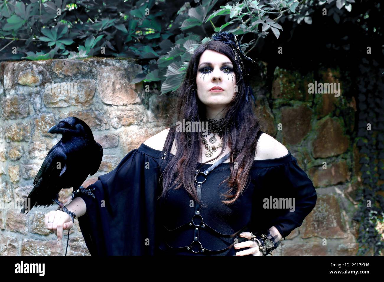 Fantasy photo of a woman dressed as a witch with a raven on her hand ...