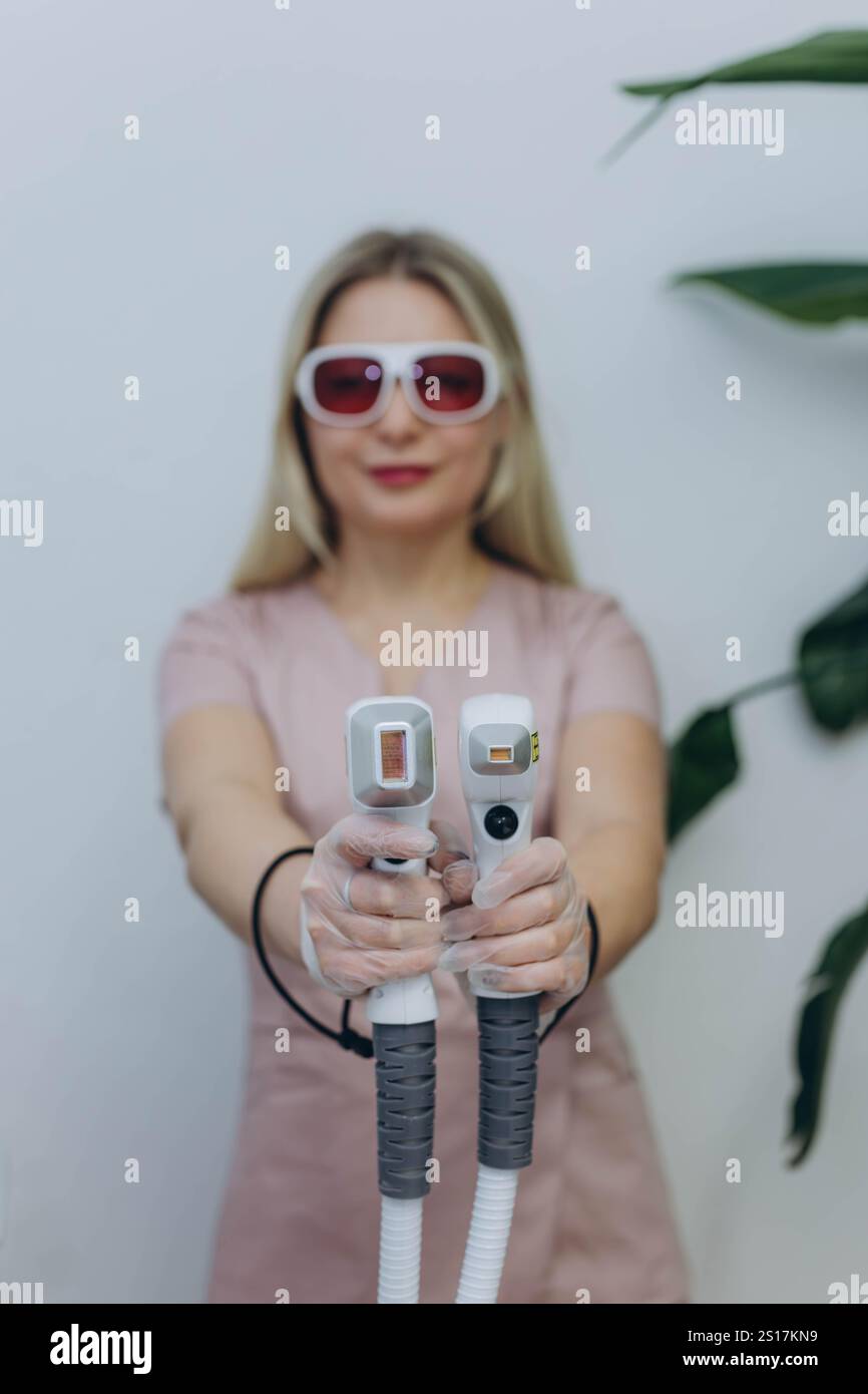 Laser hair removal specialist holding a laser device during a beauty treatment procedure. High ...
