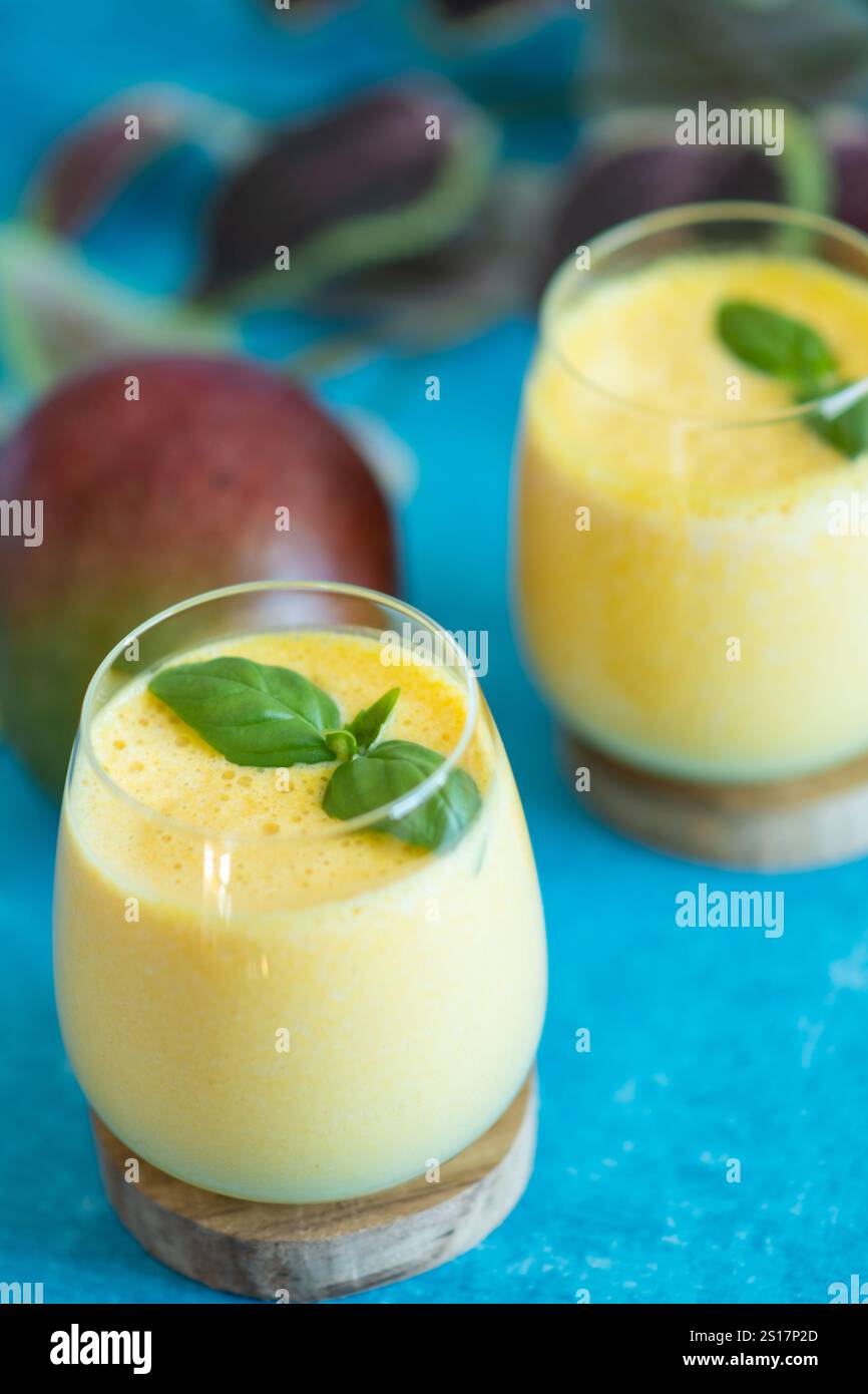 Fresh mango lassi in glasses on blue background with copy space. Indian ...