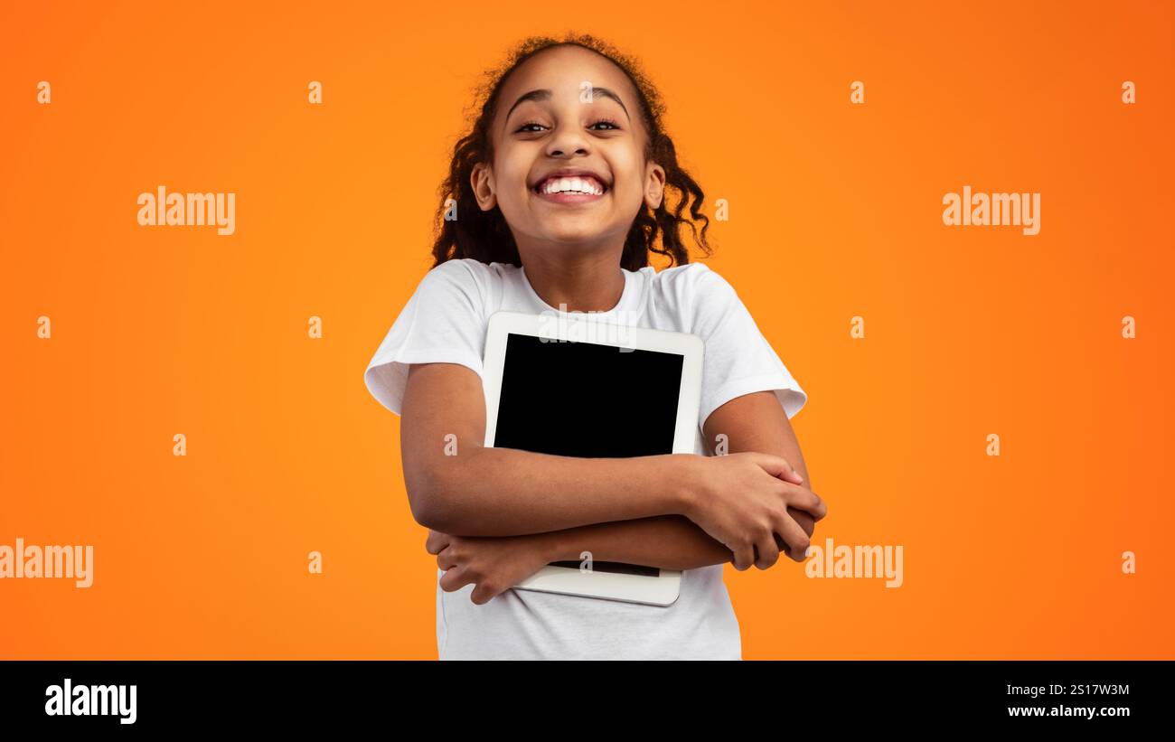 Technology Lover. Excited black girl hugging tablet Stock Photo - Alamy