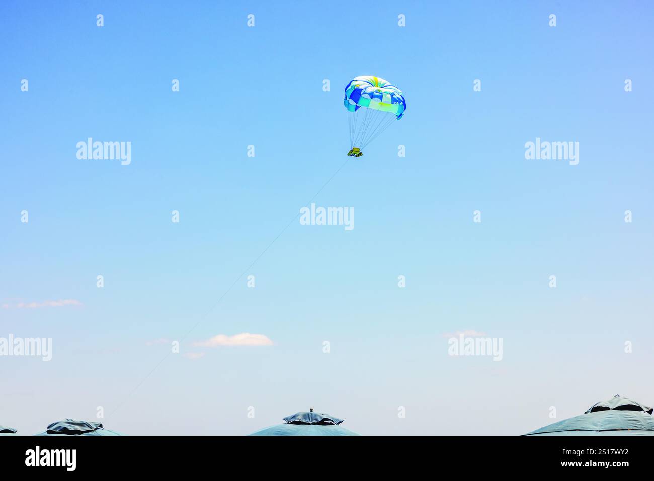 Parasailing adventure high above clear blue sky with colorful parachute ...