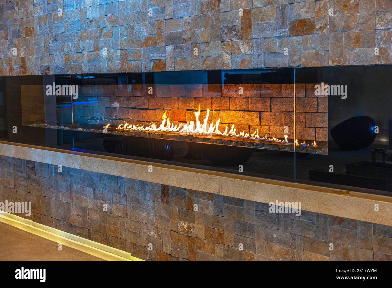 Modern linear gas fireplace with vibrant flames set against textured ...