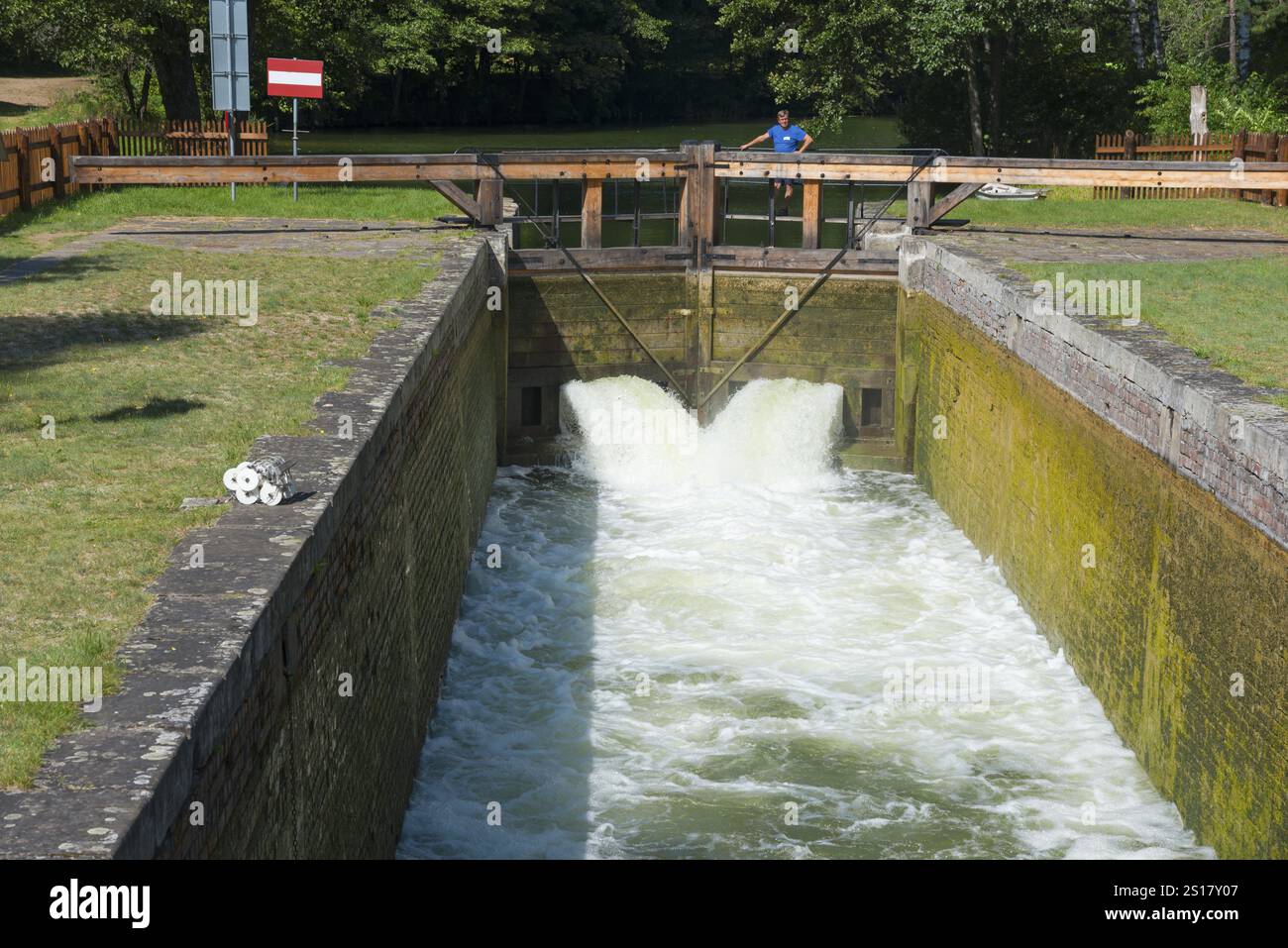 Strong water flow through an open lock with a wooden bridge, surrounded ...