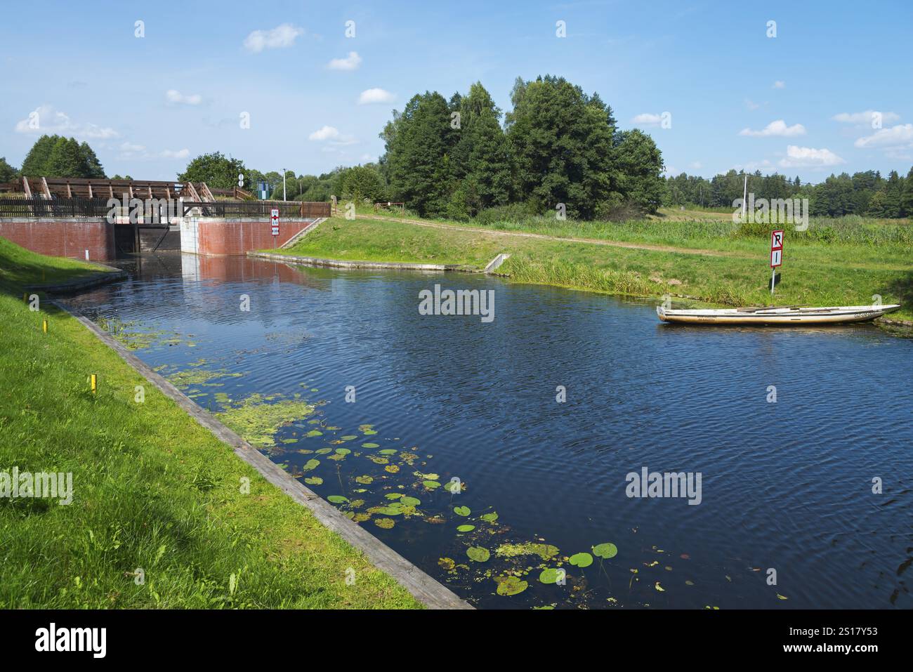 A lock is located on a river with water lilies, surrounded by green ...