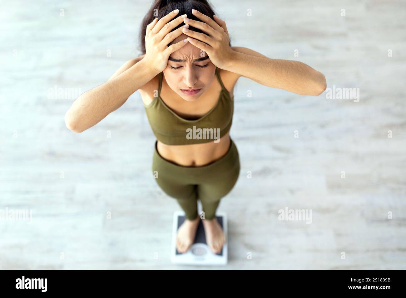 Upset young Indian woman unhappy about her weight, standing on scales ...