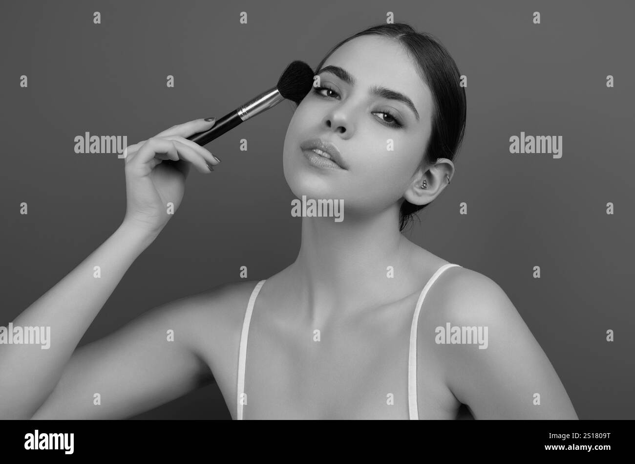 Woman applies powder on the face using makeup brush. Girl doing ...