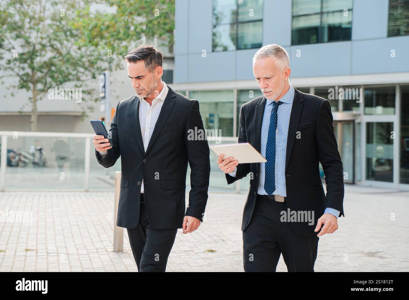 Two successful mature businessmen in formal suits walking together ...