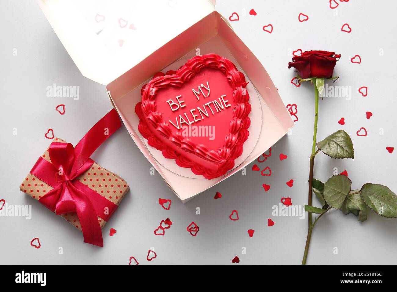 Opened box with sweet bento cake and beautiful red rose on grey ...