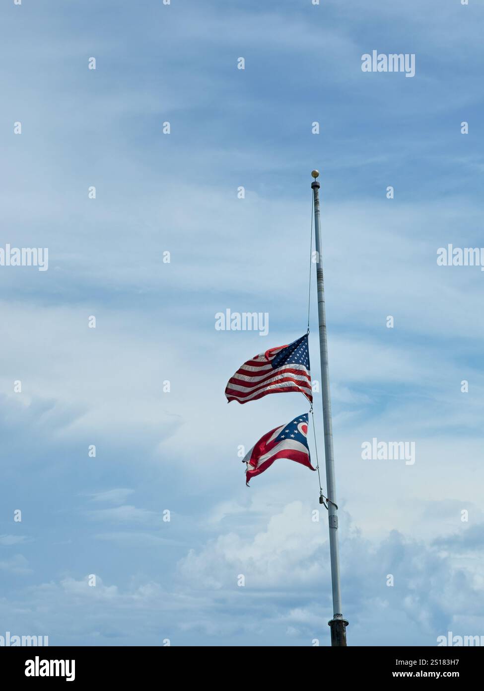 American flag and Ohio state flag on pole against dynamic cloudscape ...