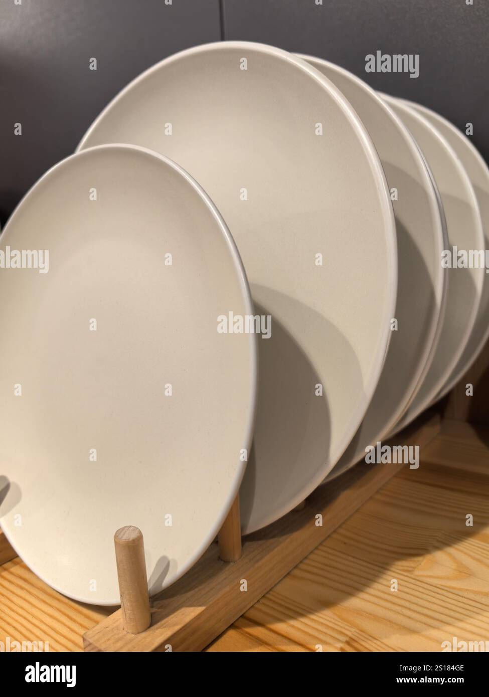 A collection of simple ceramic plates is artistically stacked on a ...